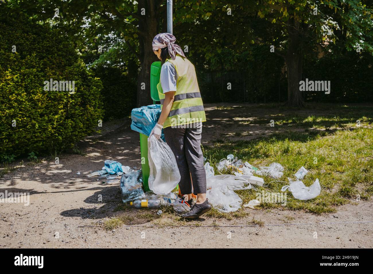 Young female environmentalist throwing plastic waste in garbage bin ...