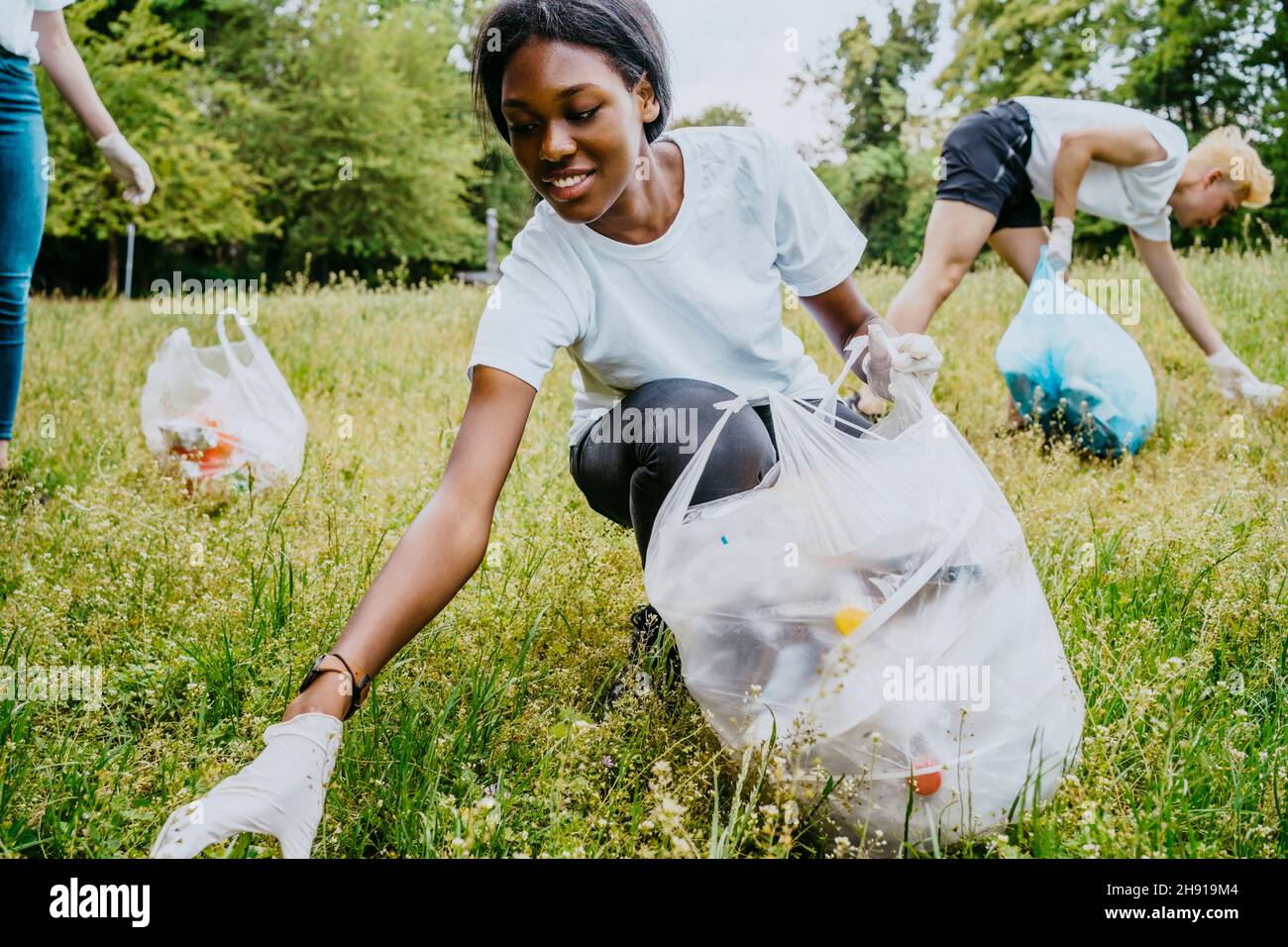 Female and male environmentalists picking up plastic waste at park ...