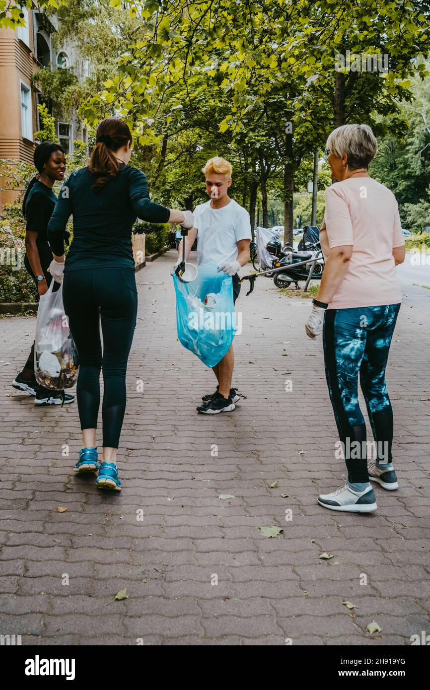 Female and male volunteers picking up plastic waste on footpath Stock ...