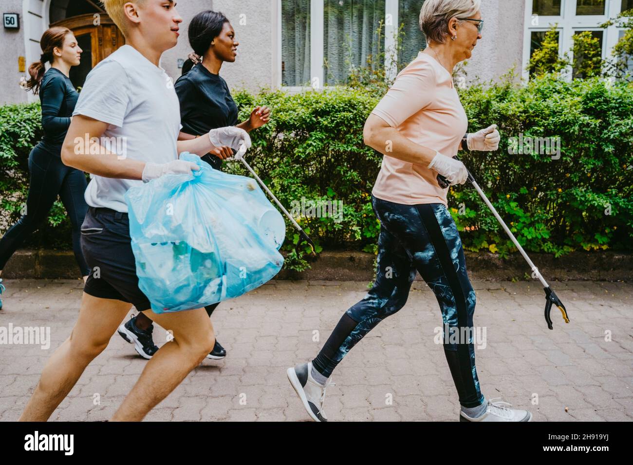 Male and female environmentalists plogging with plastic bag on footpath ...