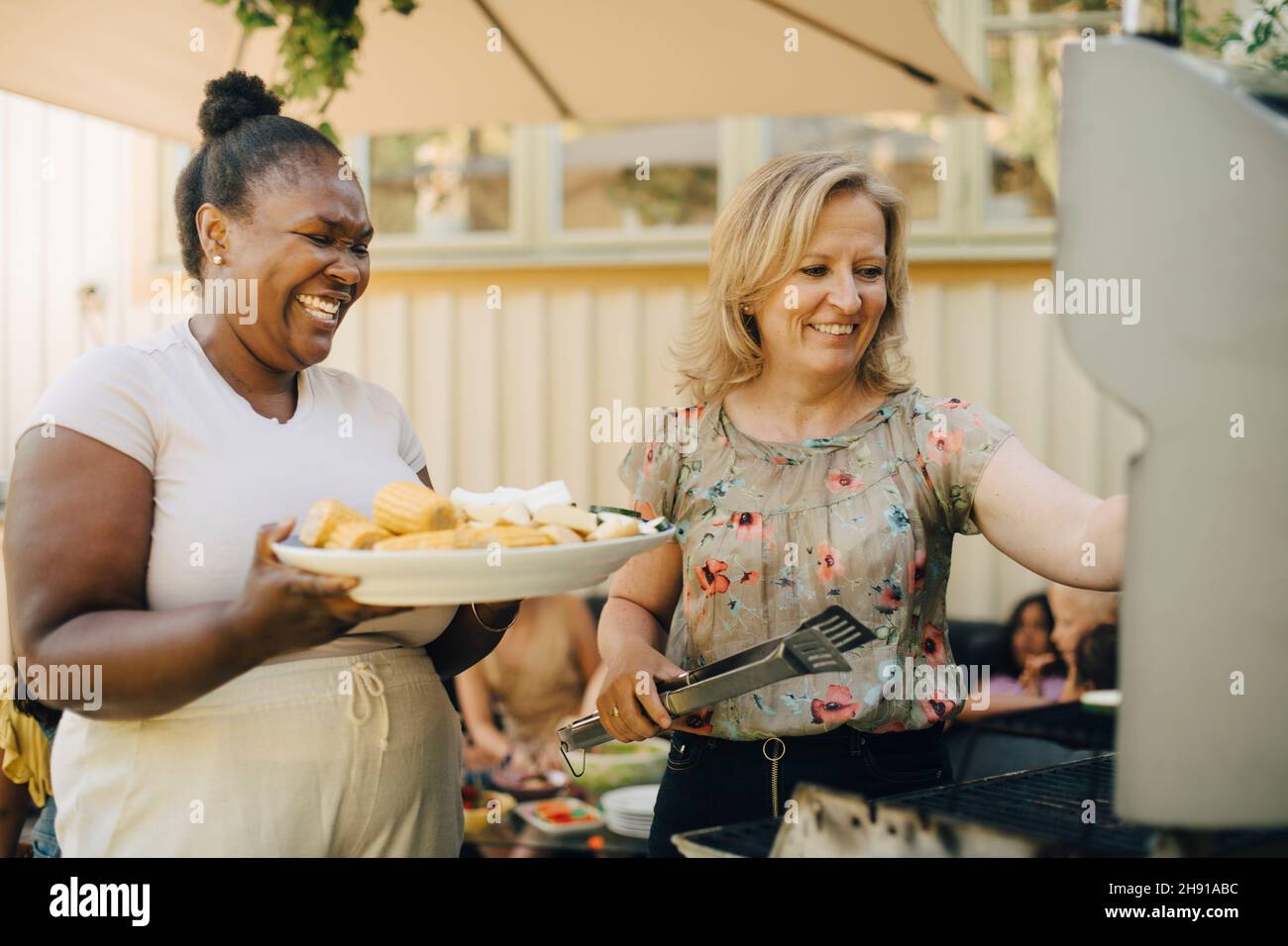Happy women preparing food on barbecue grill during dinner party Stock ...