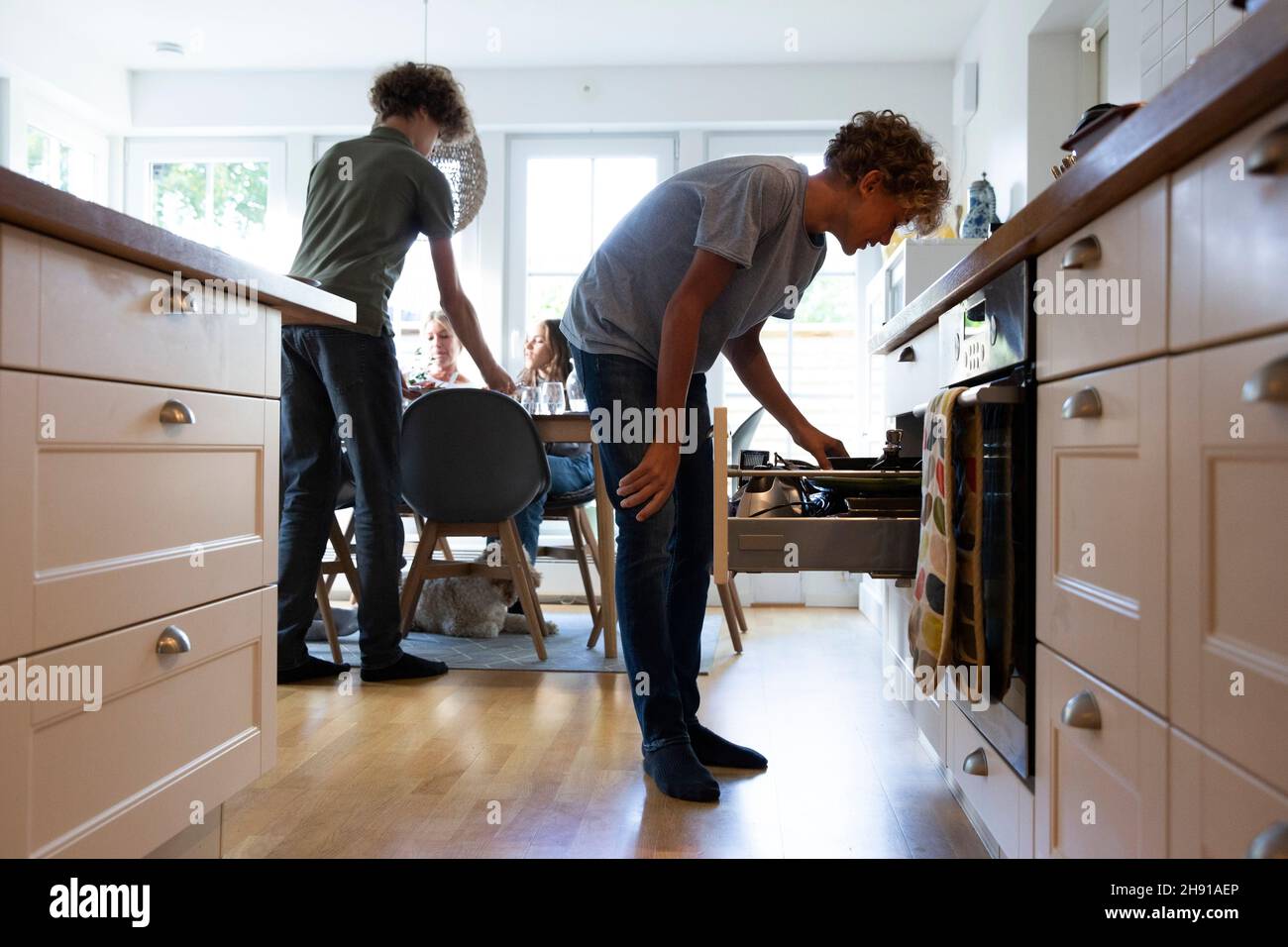 Boy searching in drawer while family at dining table Stock Photo - Alamy