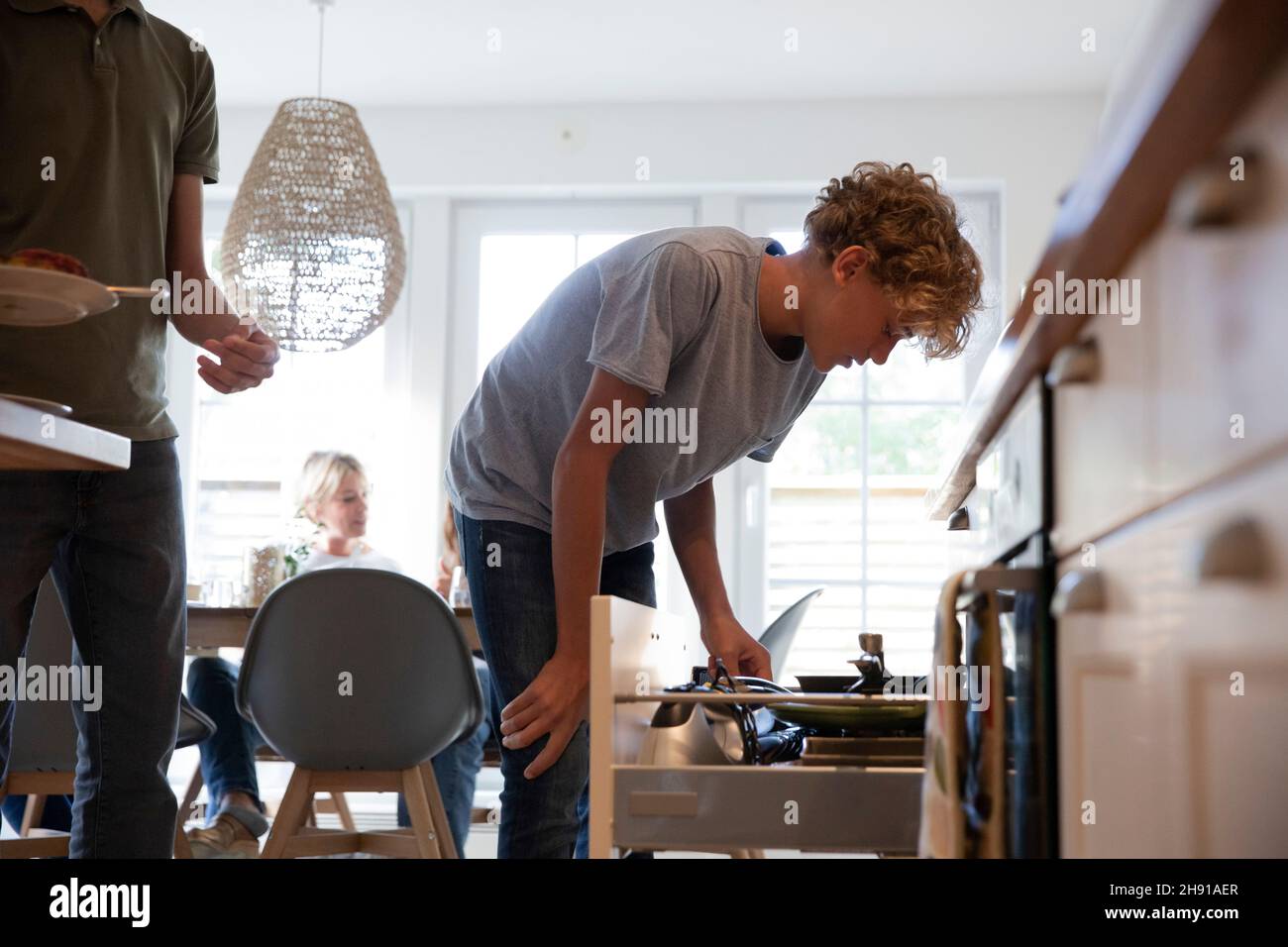 Boy doing kitchen chores while searching in drawer at home Stock Photo ...