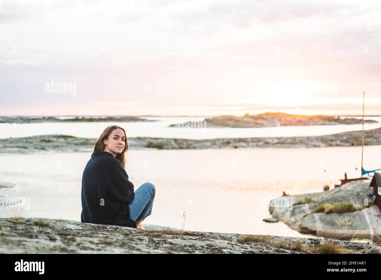 Woman looking over shoulder while sitting on island during sunset Stock ...