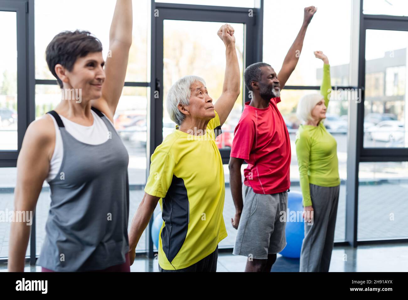 Grey haired asian man training near multiethnic people in gym Stock ...