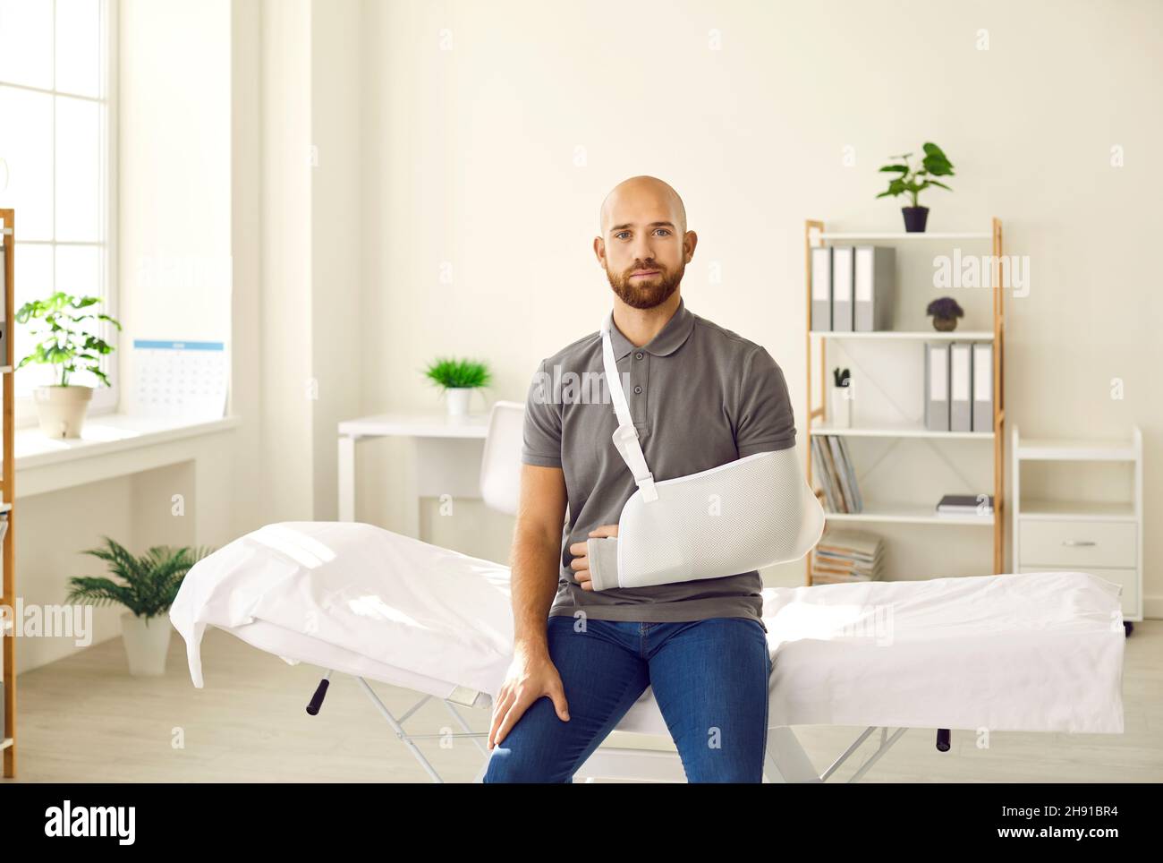Male patient with support brace and sling on his broken arm at clinic ...