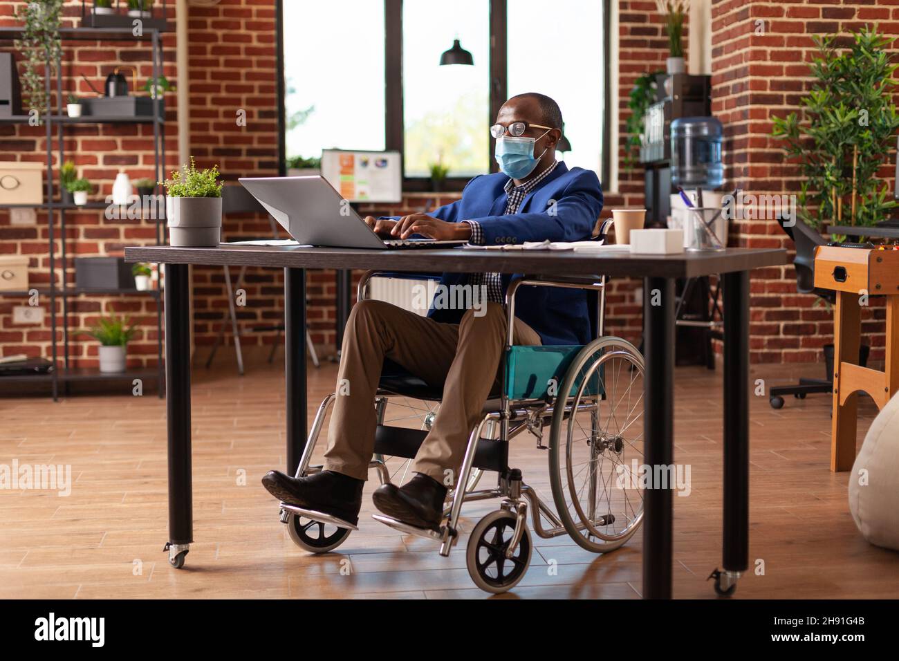 Employee with disability wearing face mask and working on business ...