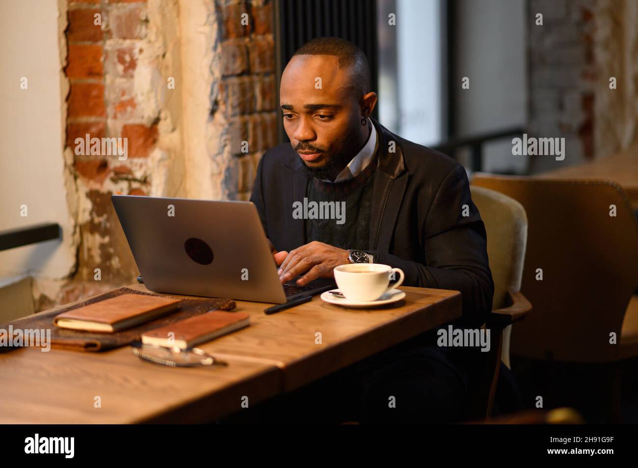 African-American man is working at a laptop in a cafe. Free work ...