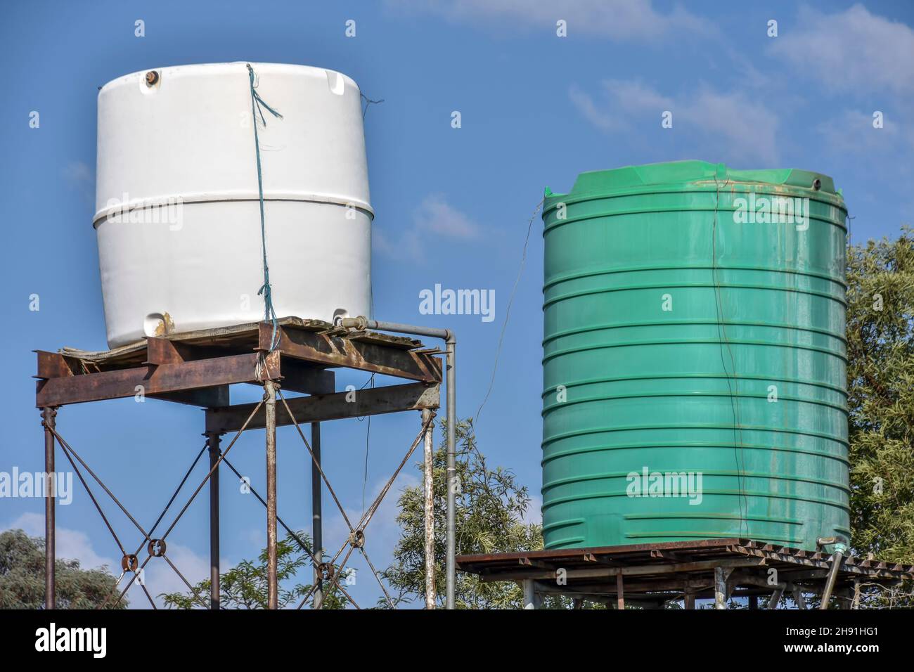 Green and white plastic water tanks or containers on an elevated metal ...