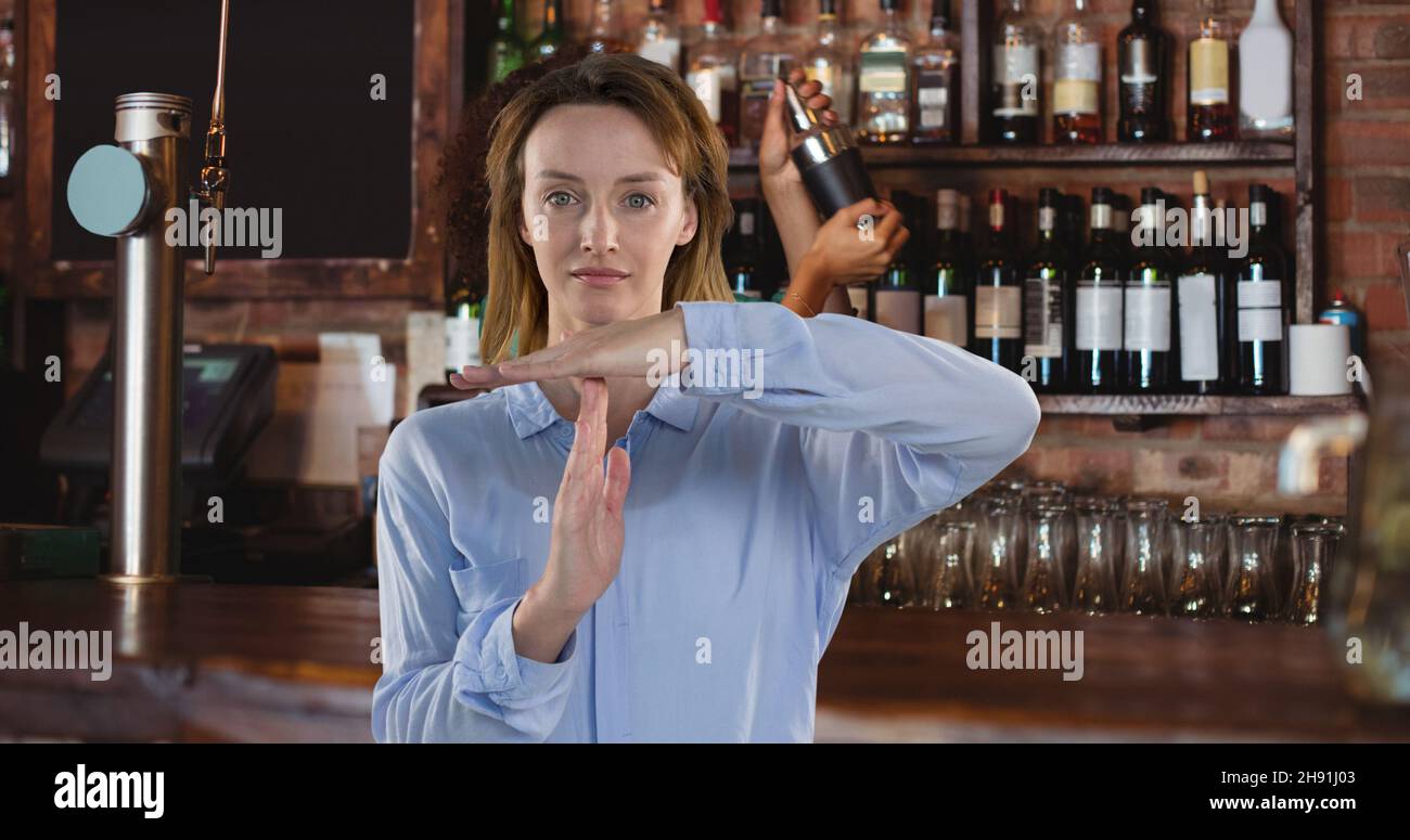 Portrait of young woman showing time out sign with hands at bar Stock ...