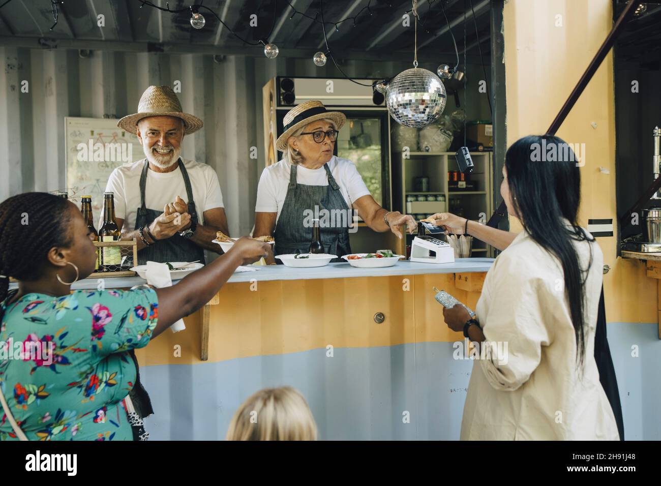 Female customer paying through credit at food truck Stock Photo - Alamy