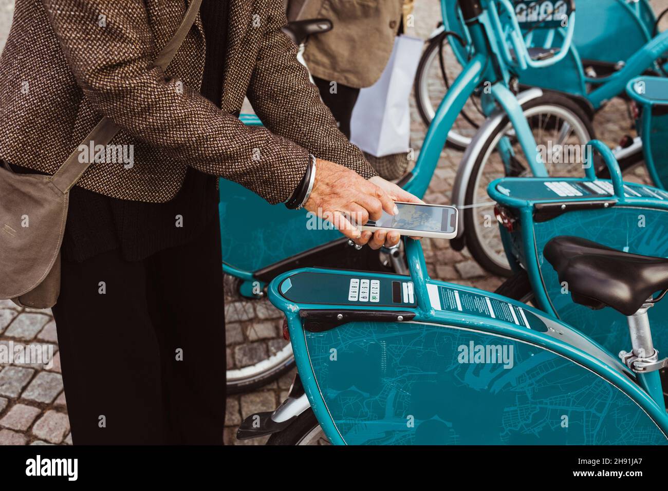 Midsection of senior woman scanning QR code of bicycle through smart ...