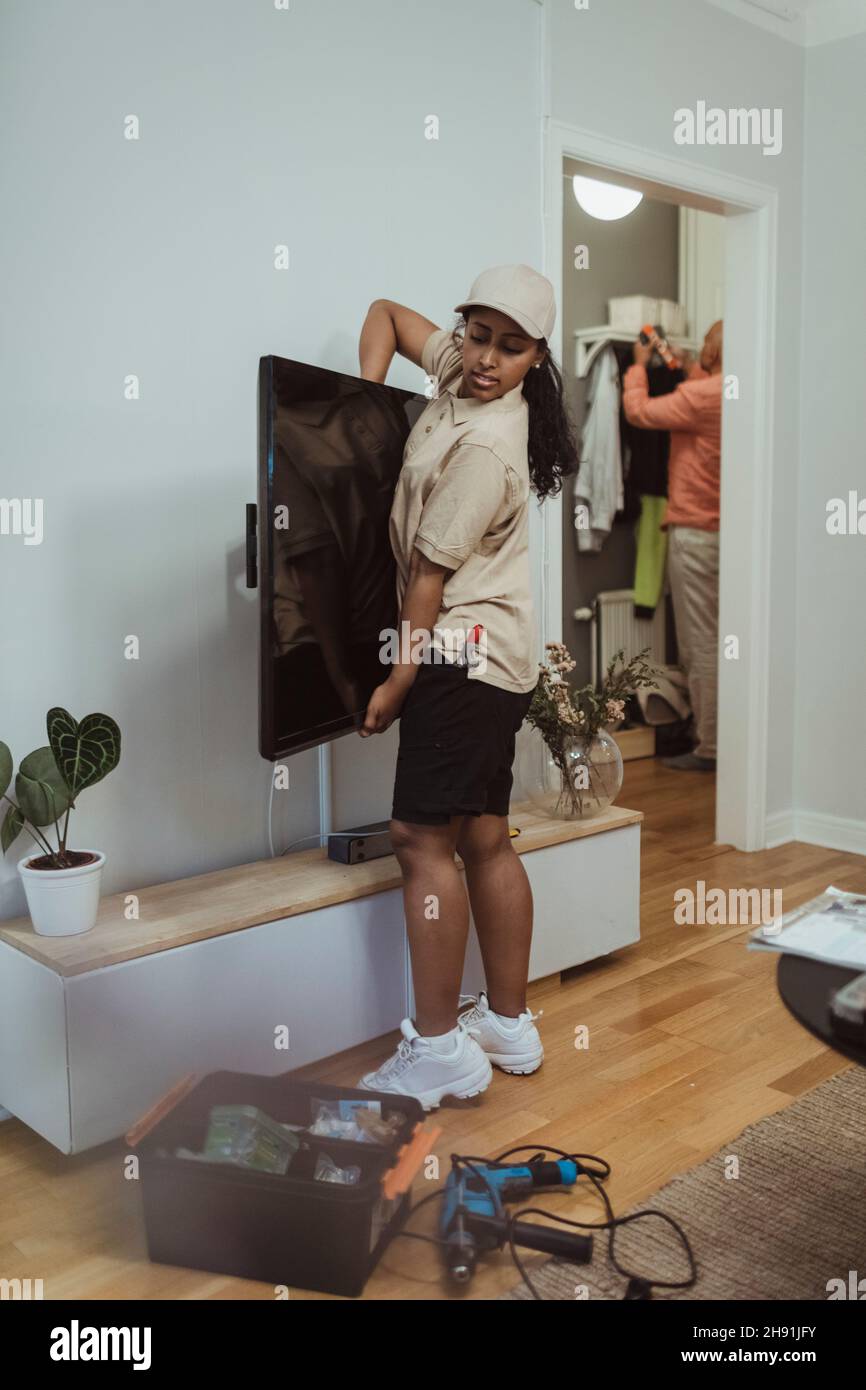 Female technician fixing television set in living room Stock Photo - Alamy