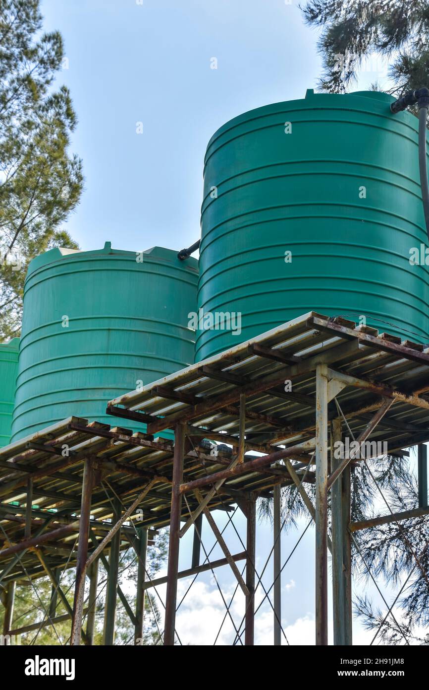 Green plastic water tanks or containers on an elevated metal structure ...