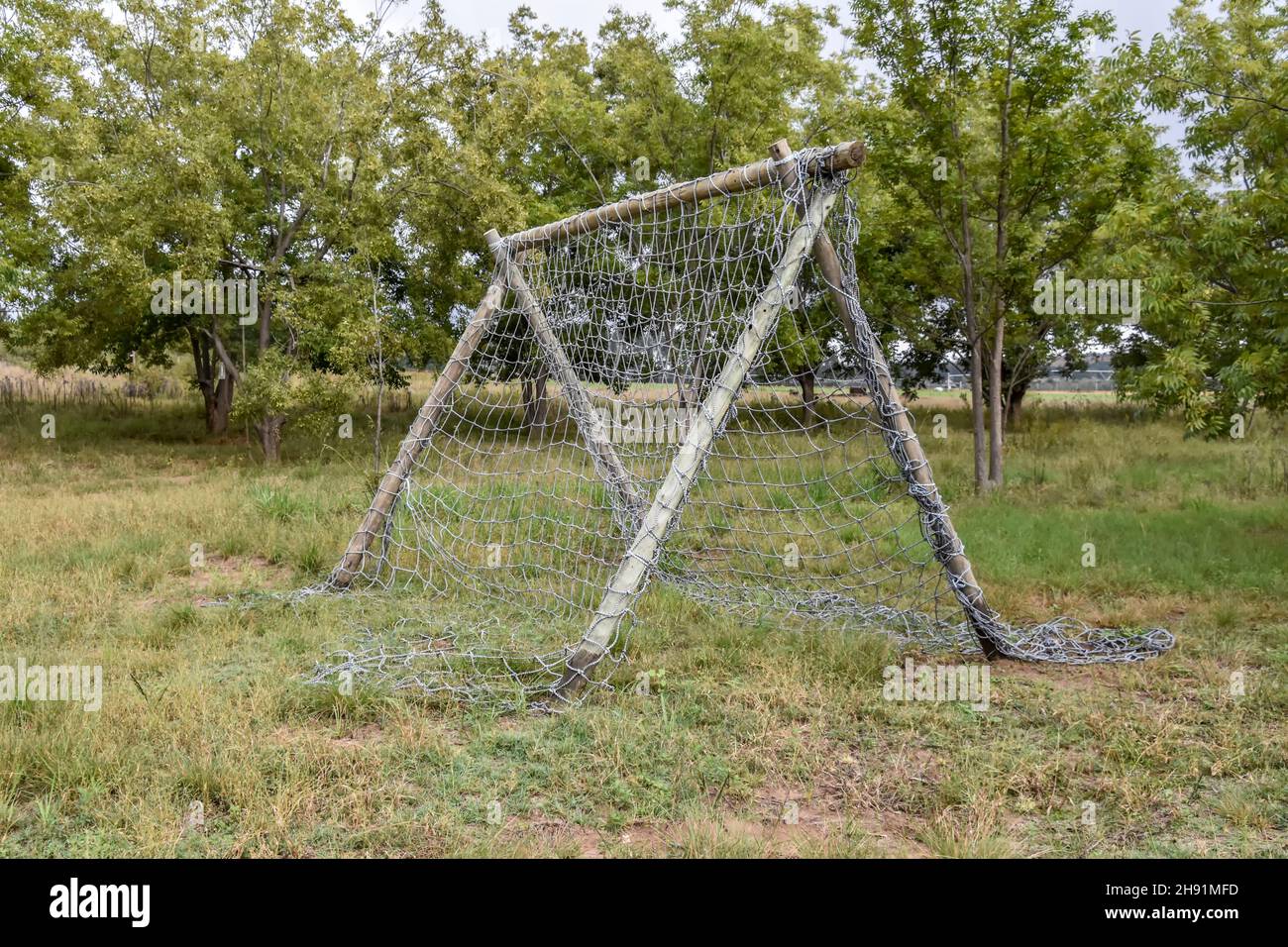 A climbing rack made of wooden poles and a net made for an obstacle ...