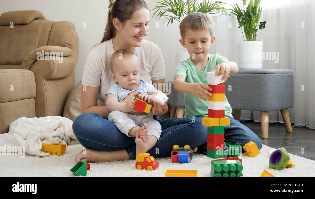 Smiling happy family building high tower with toy blocks and bricks ...