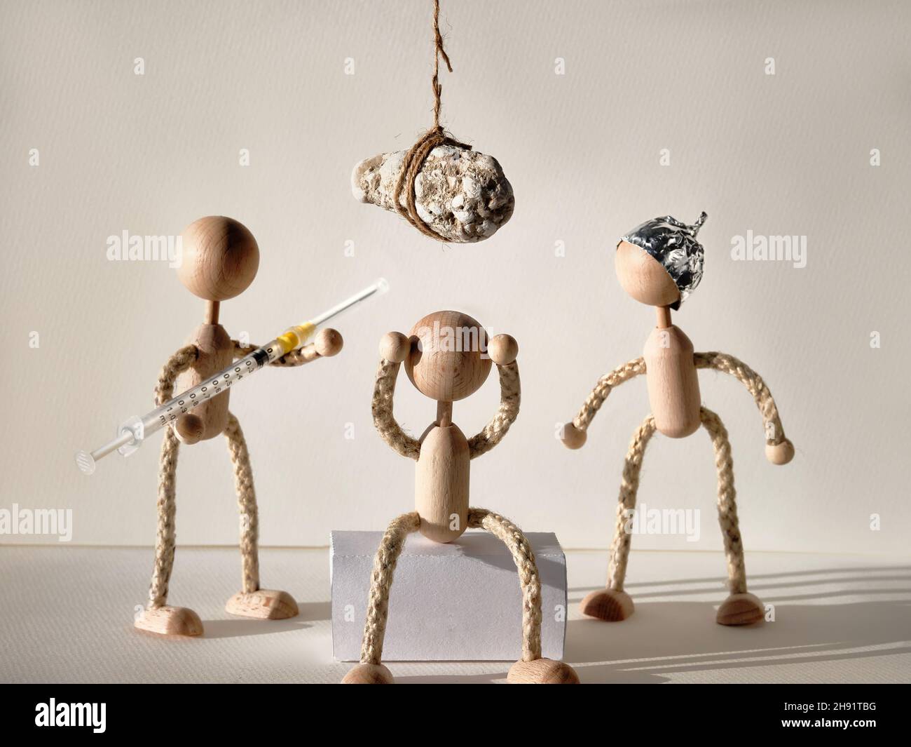 Confused wooden toy man in fear of heavy stone above his head ...