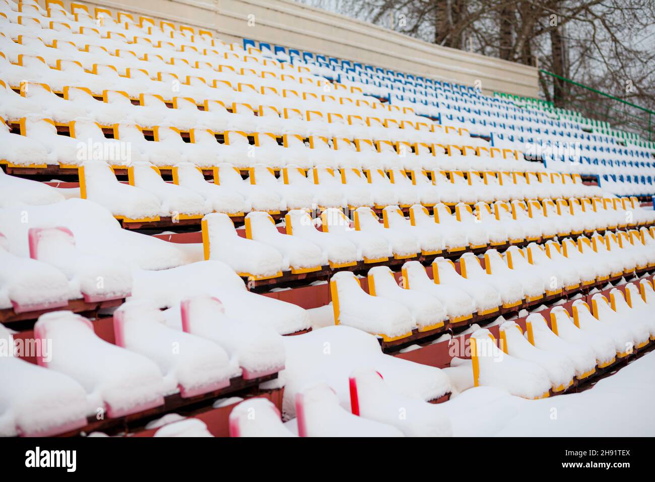 Empty outdoor football soccer stadium seats covered with snow in winter ...