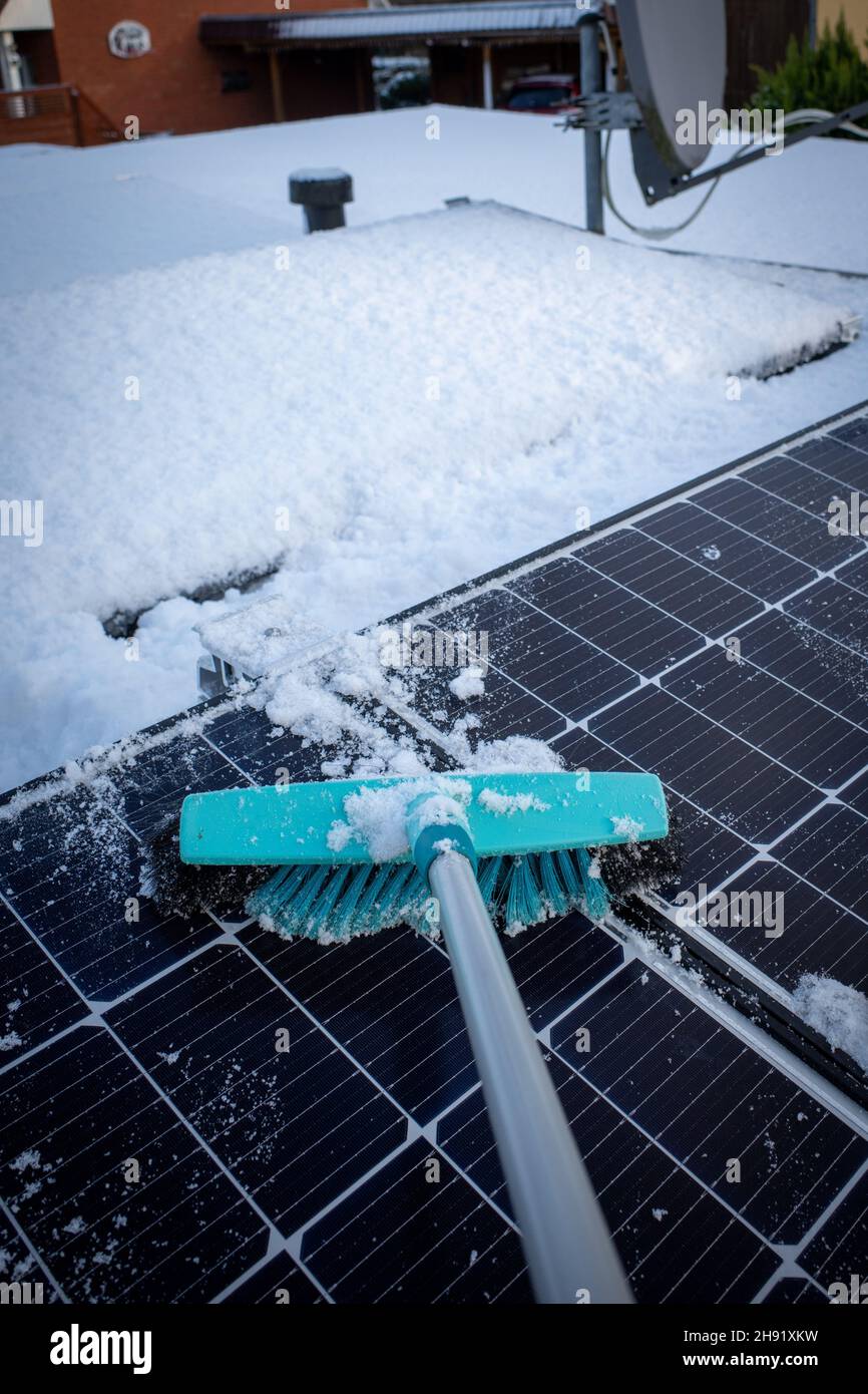 Solar panels of a photovoltaic system on a roof are cleared of snow ...