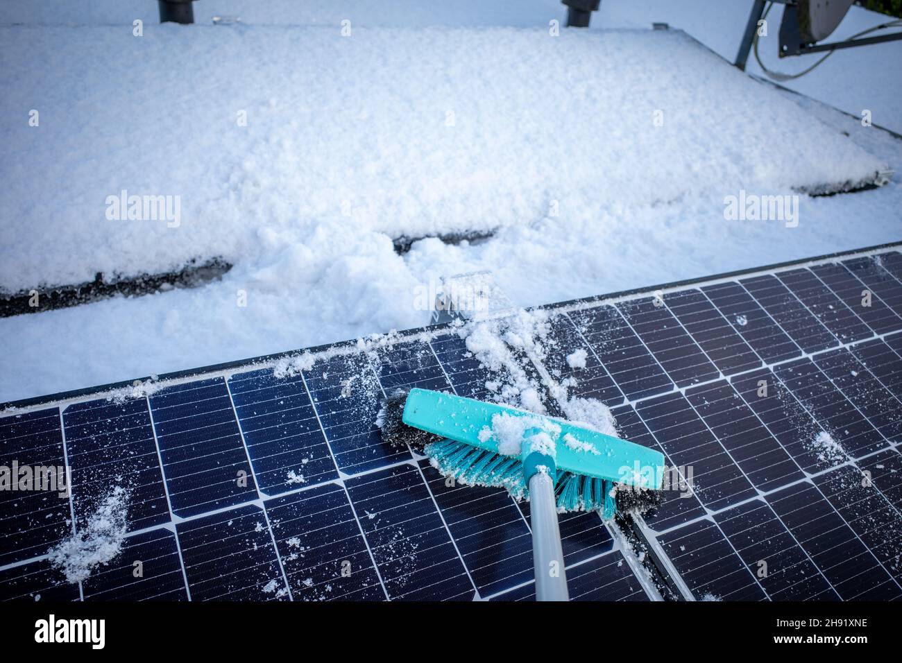 Solar panels of a photovoltaic system on a roof are cleared of snow ...