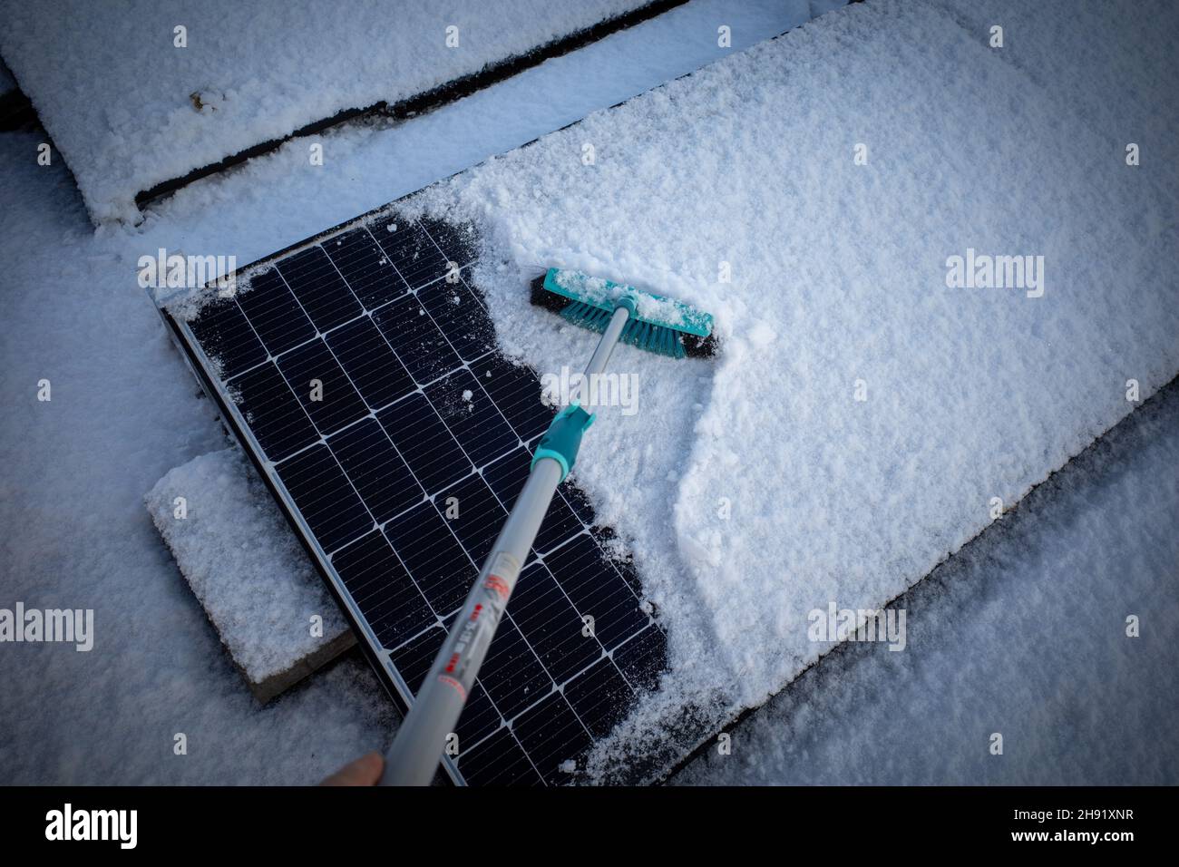 Solar panels of a photovoltaic system on a roof are cleared of snow ...