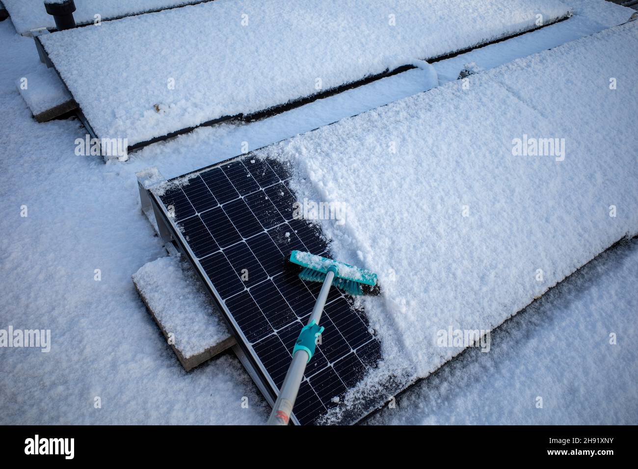 Solar panels of a photovoltaic system on a roof are cleared of snow ...