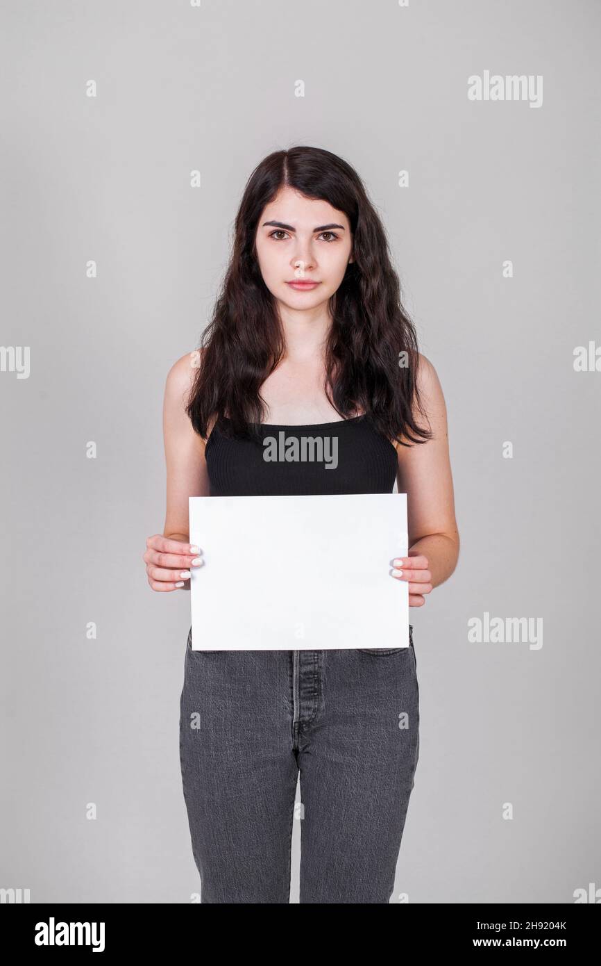 Young beautiful girl holding a blank sheet of paper in her hands ...
