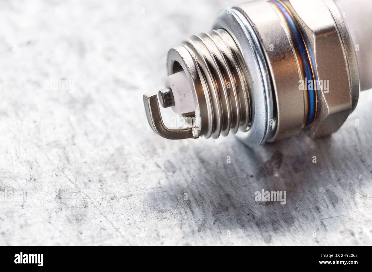 Closeup photo of new spark plug for internal combustion engine on metal ...