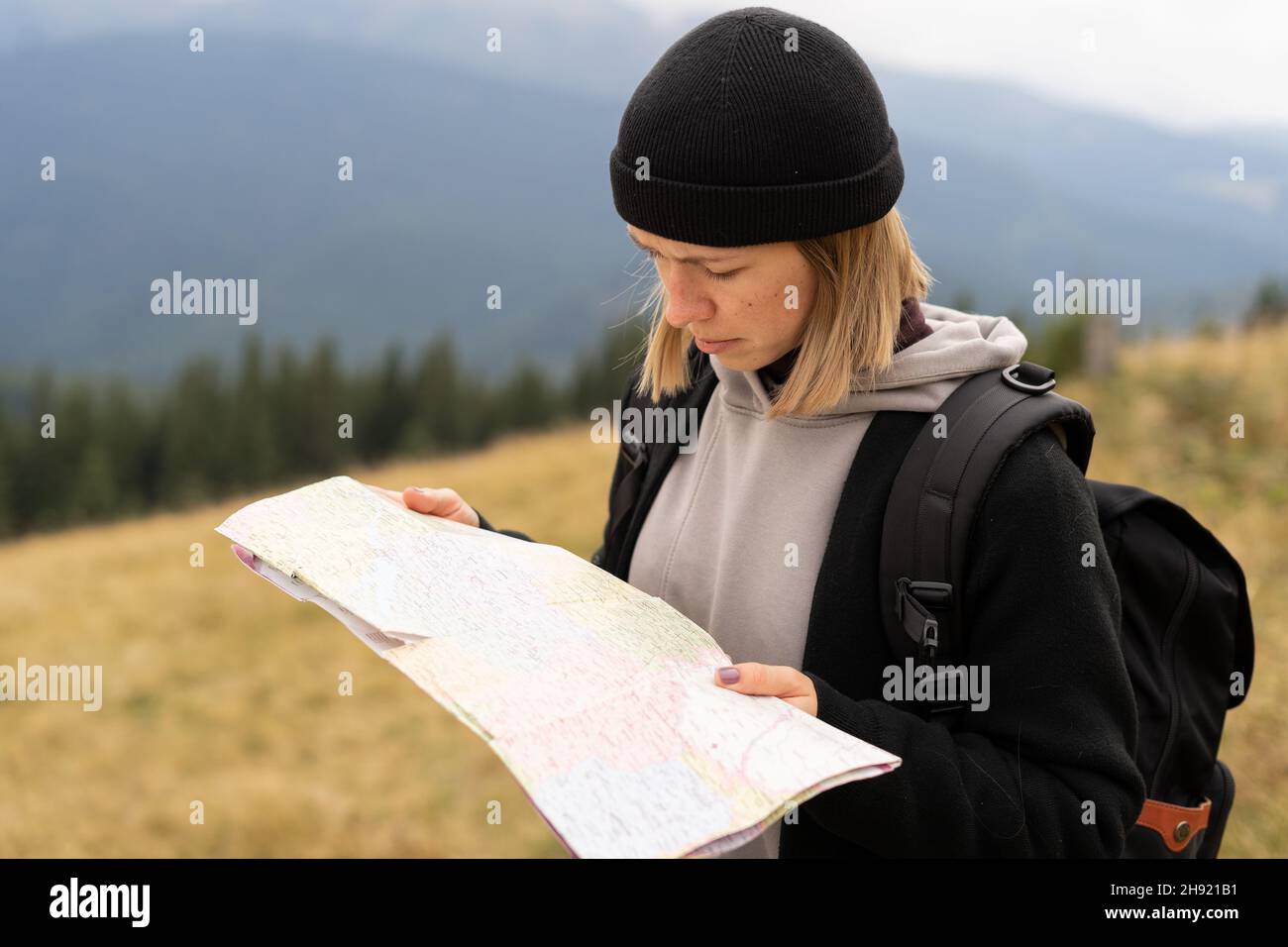 girl tourist in the mountains reading a map, portrait of a traveler in ...