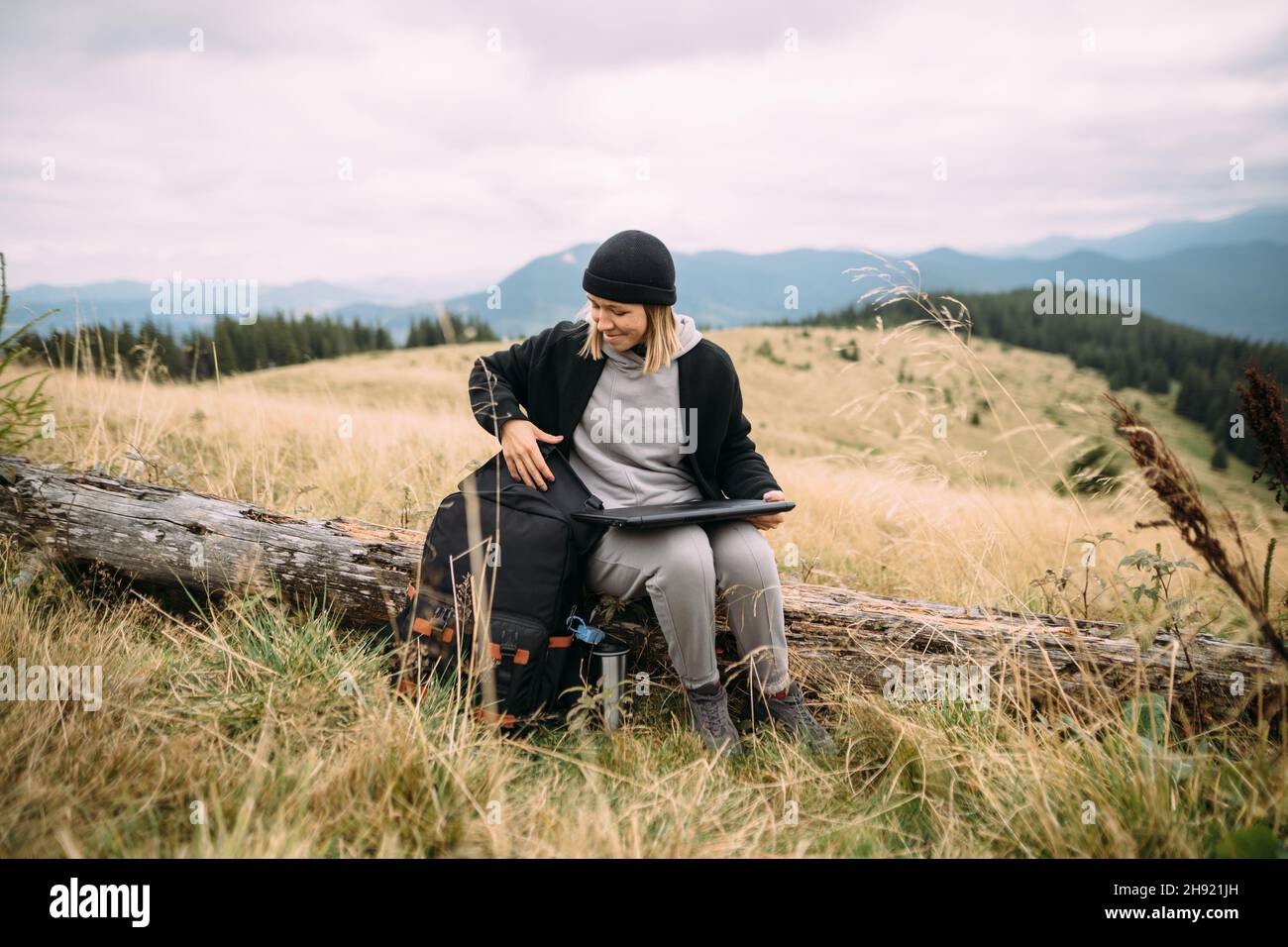 woman working with laptop sitting in the mountains. Caucasian lady ...