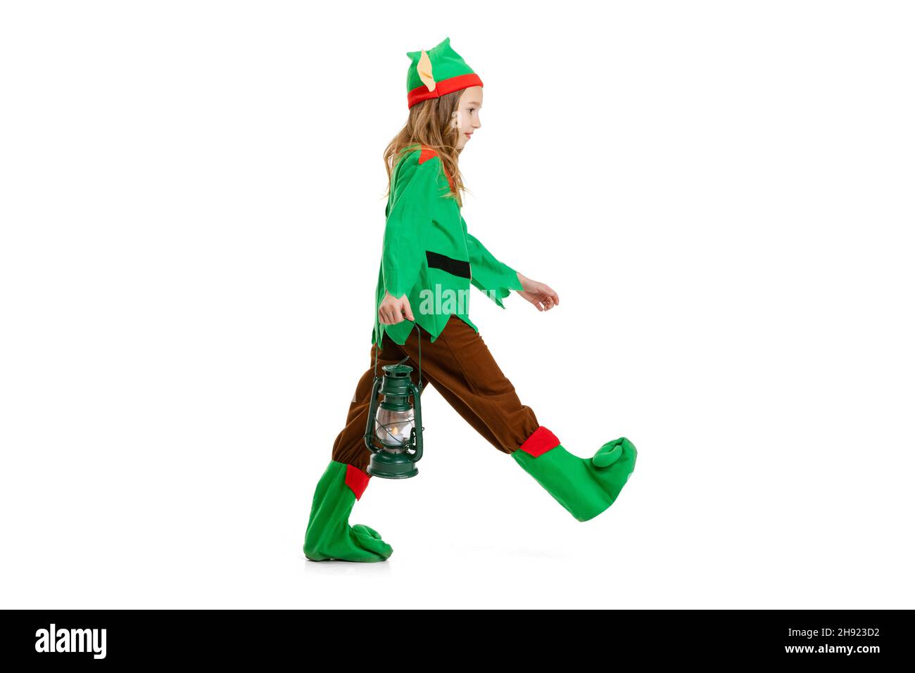 Side view of little girl dressed like funny gnome or elf walking ...