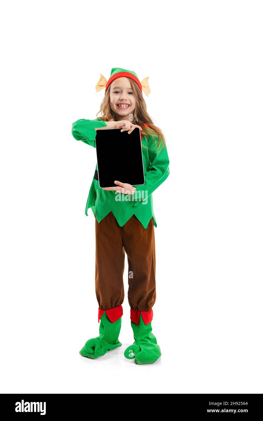 Cute smiling girl dressed like funny gnome or elf using tablet, gadget ...