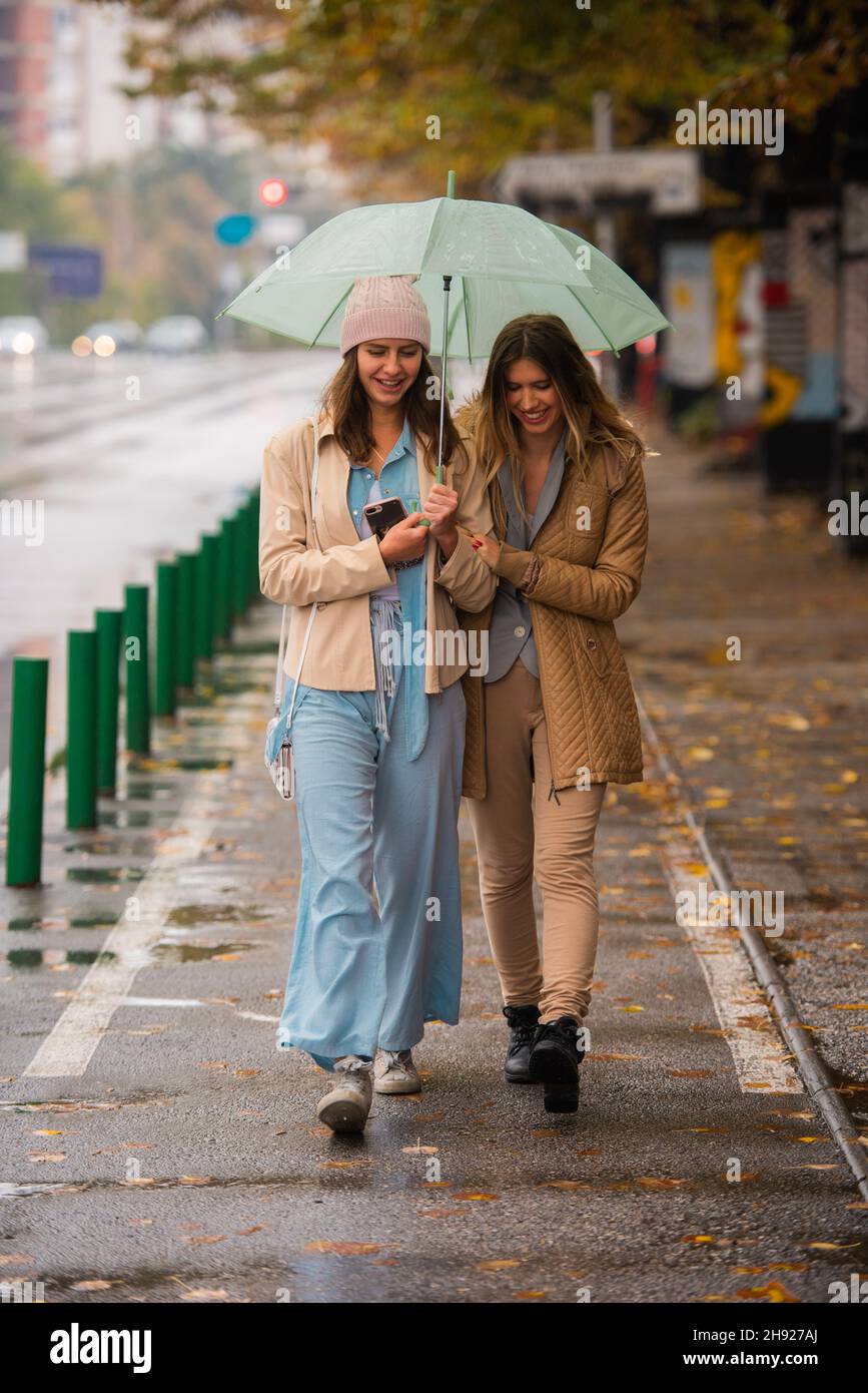Attractive and amazing stwo sisters are laughing while walking together ...