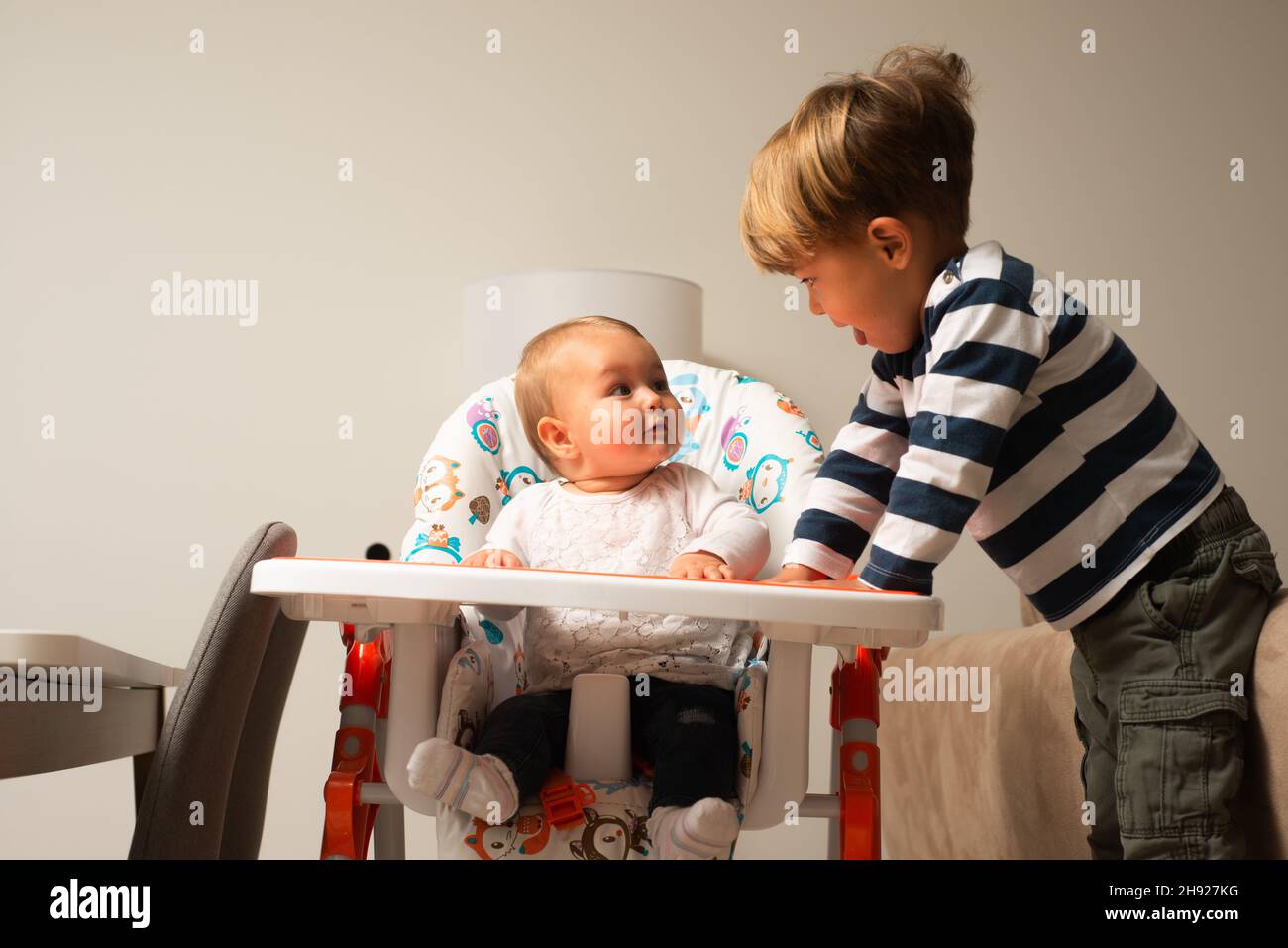 Adorable siblings are talking to each other while standing next to each ...