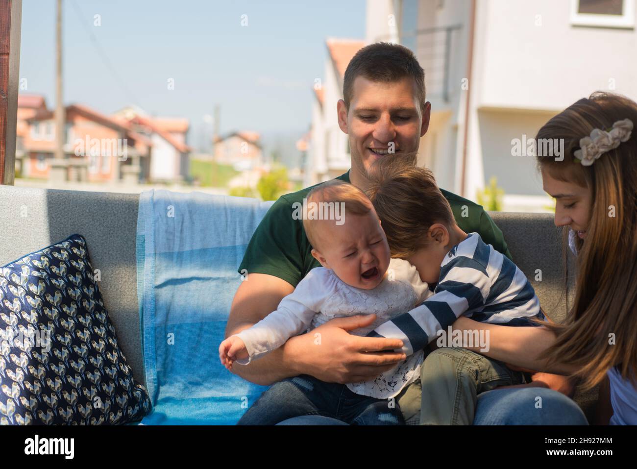 Young brother is hugghing his crying baby sister while the parents are ...