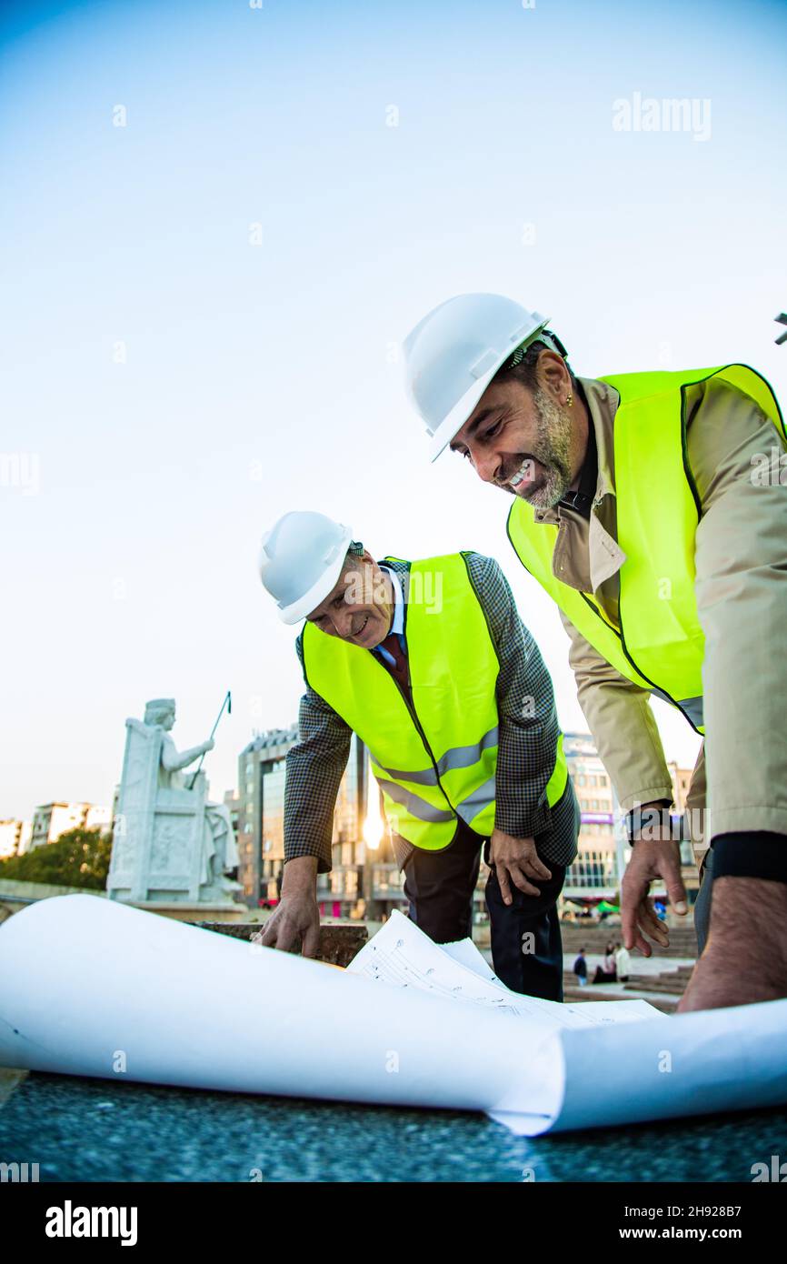 Two construction workers are smiling and looking at the plans, low ...