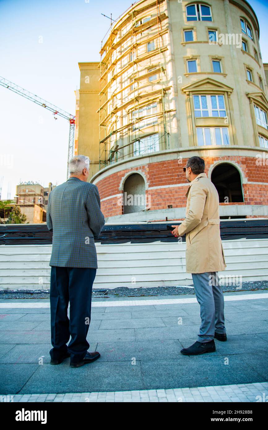 Two seniors businessmen are talking to each other about the buildings ...