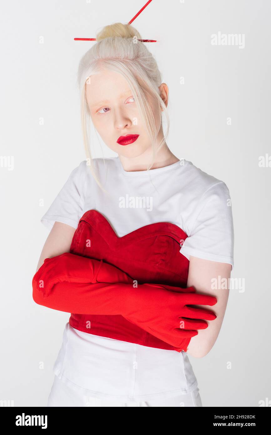 Pretty albino model in red gloves and hair sticks crossing arms ...