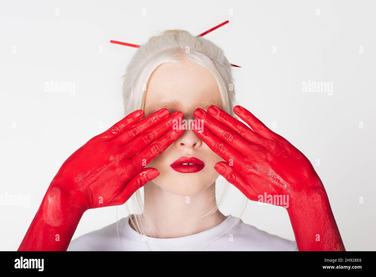 Female hands in paint covering eyes of albino model isolated on white ...
