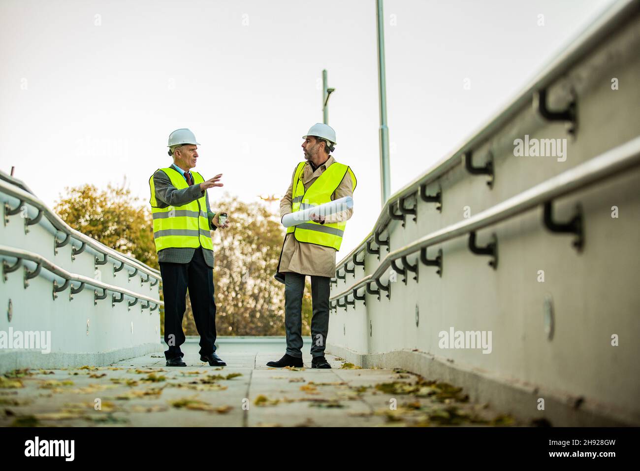 Two senior construction managers are standing and having a conversation ...