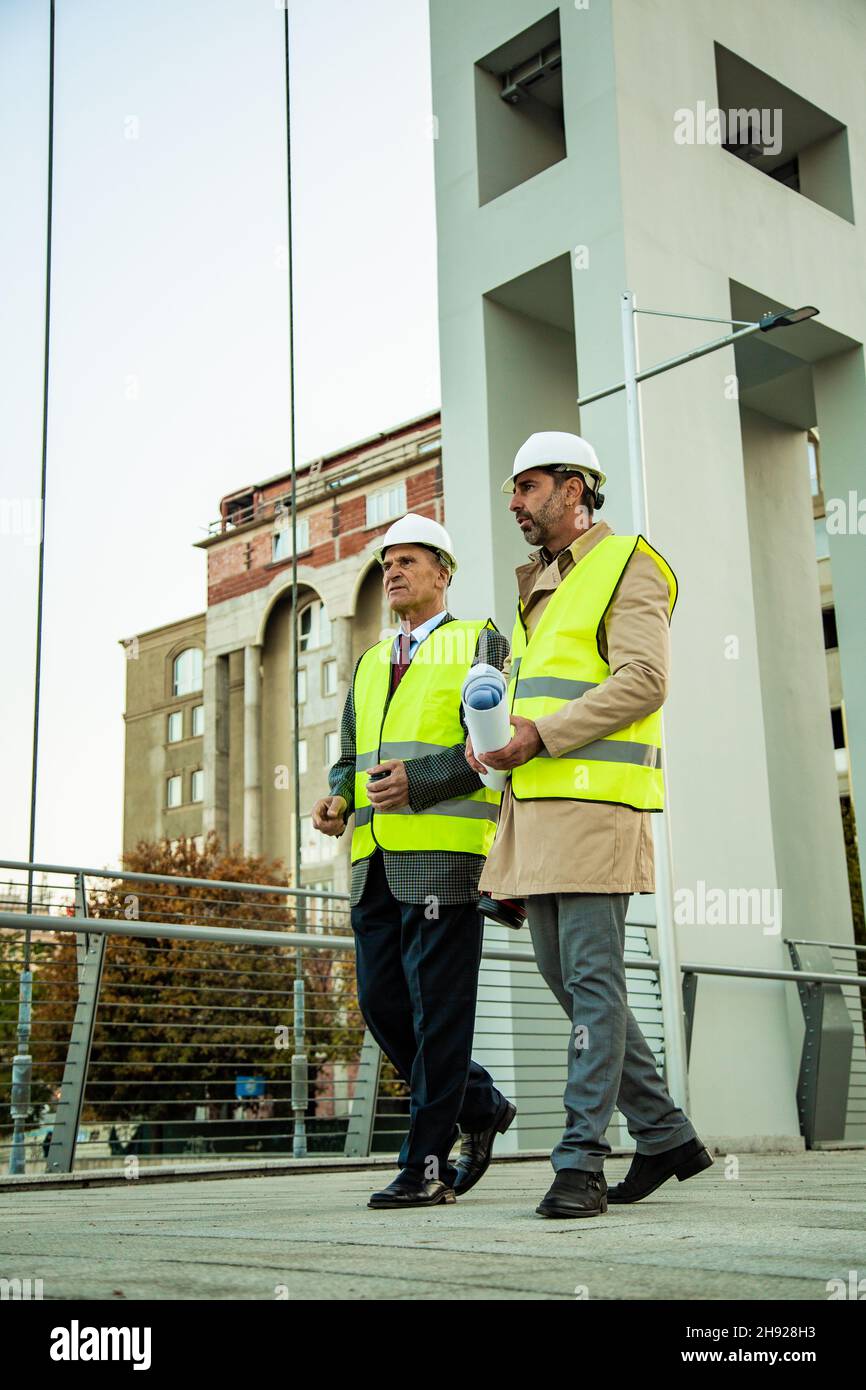 Two senior construction workers are walking together towards the ...