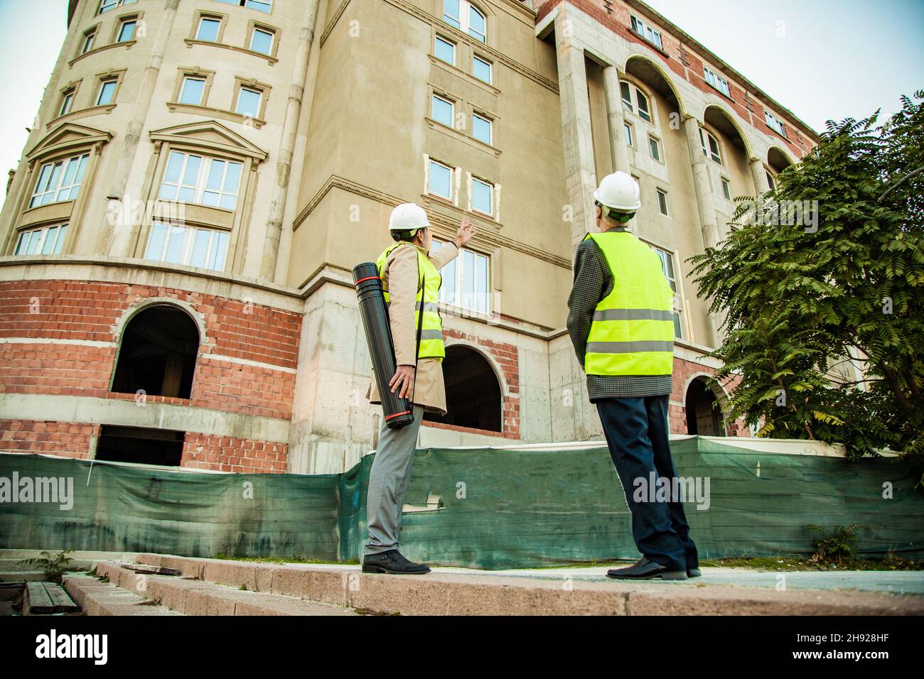Two senior construction workers are standing and looking at the ...