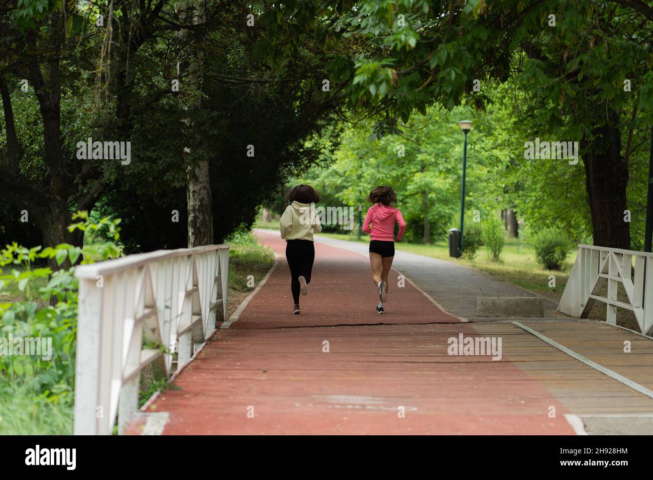 Two atttractive and young girls are running on their red running track ...