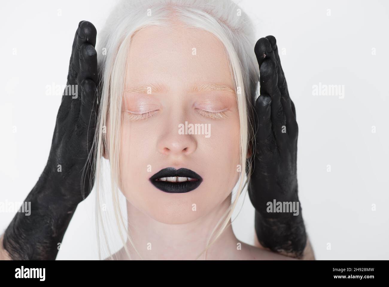 Male hands in black paint covering ears of albino model isolated on ...