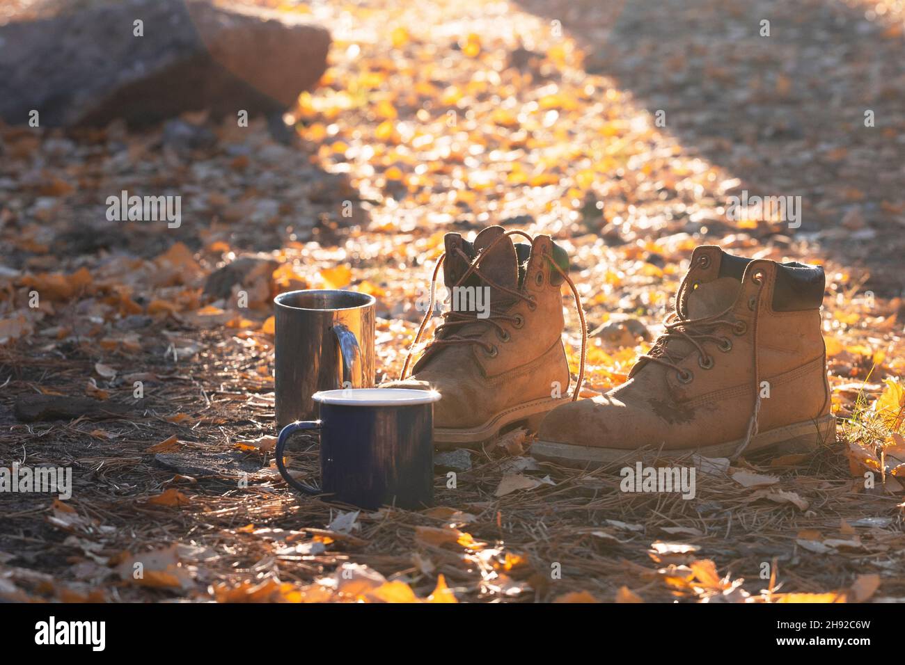 a camping aesthetics. cups with tea and boots in the dawn light Stock ...