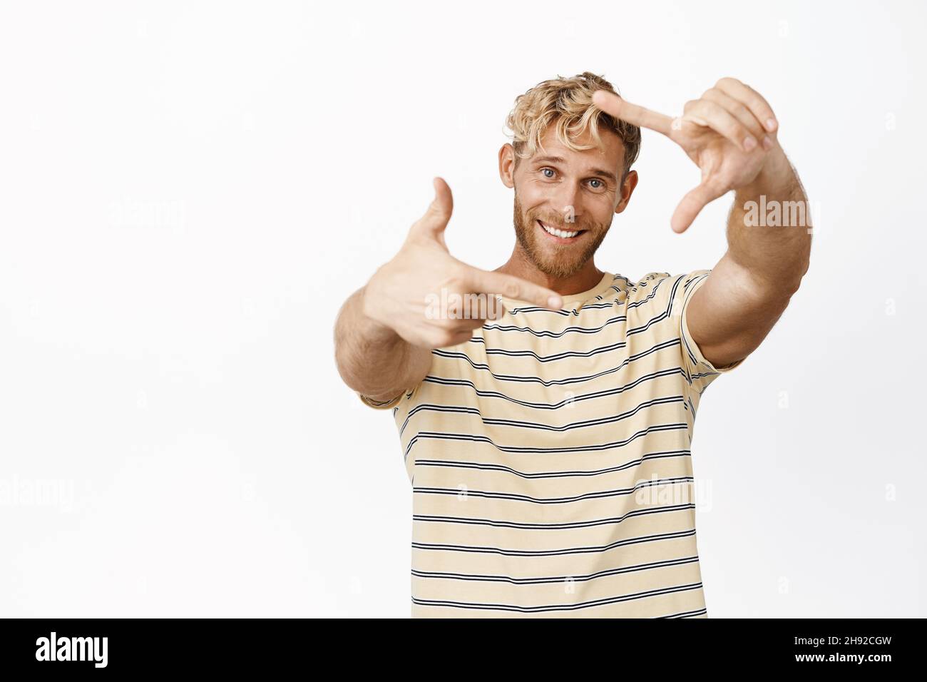 Image of smiling blond guy stretching out hands frame and looking happy ...