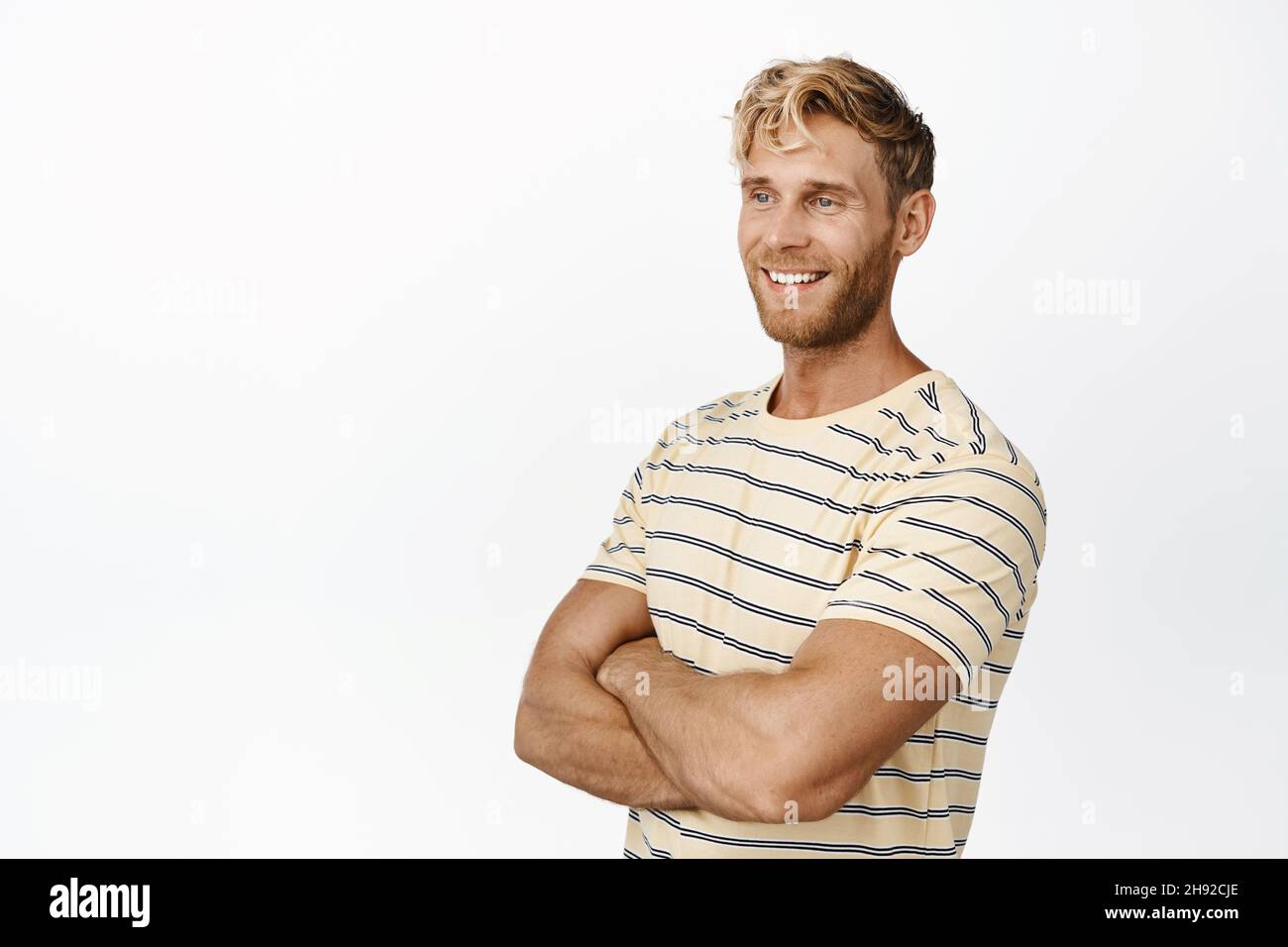 Portrait of blond male model cross arms, smiling and looking aside at ...