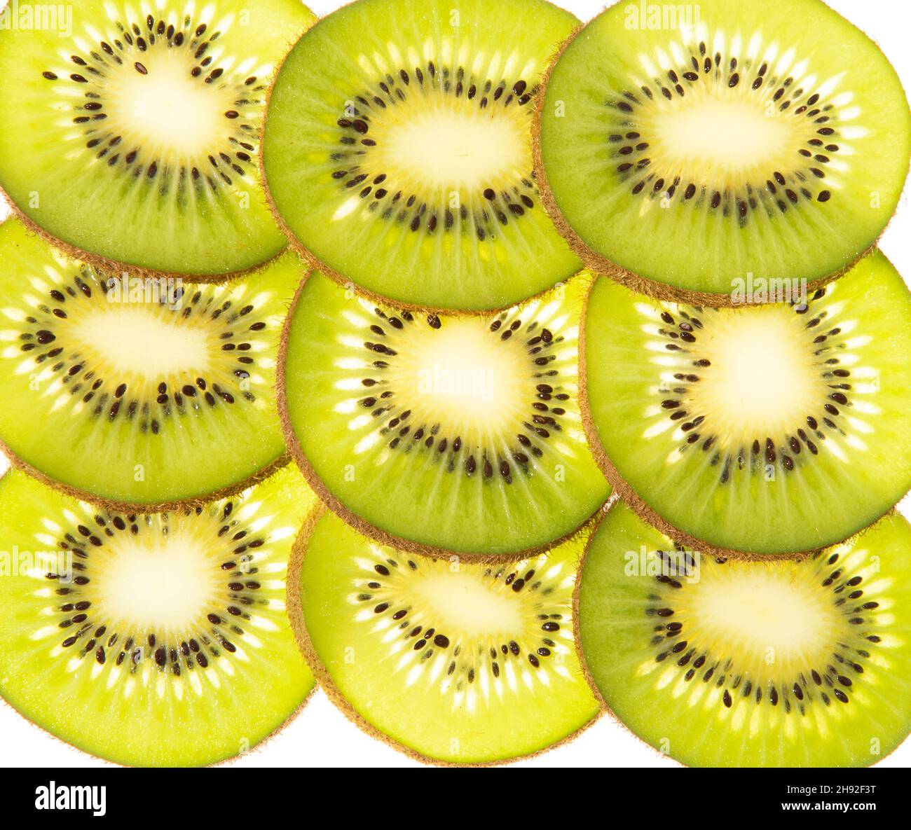 Slices of a Kiwi fruit arranged in a regular pattern with back lighting ...