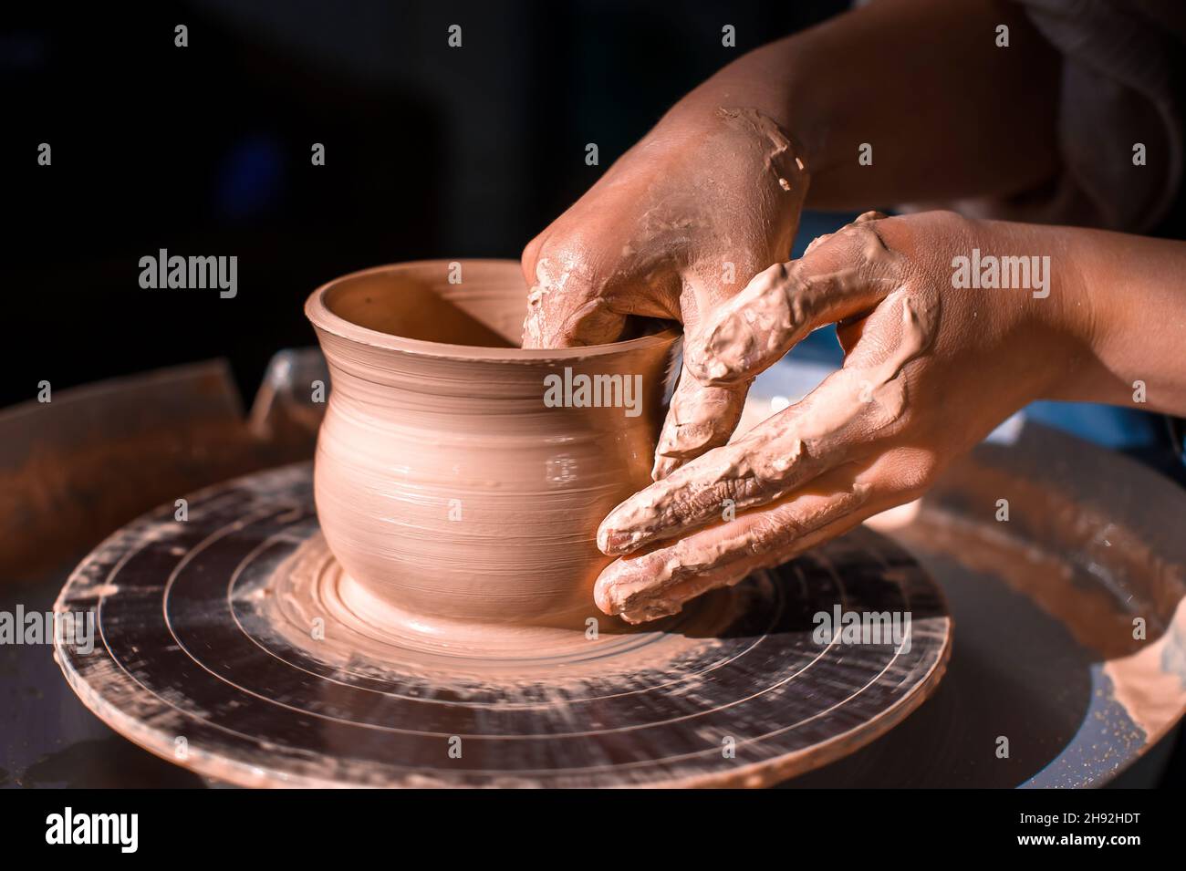 Potter master woman sculptor works with clay on a Potter's wheel and at ...