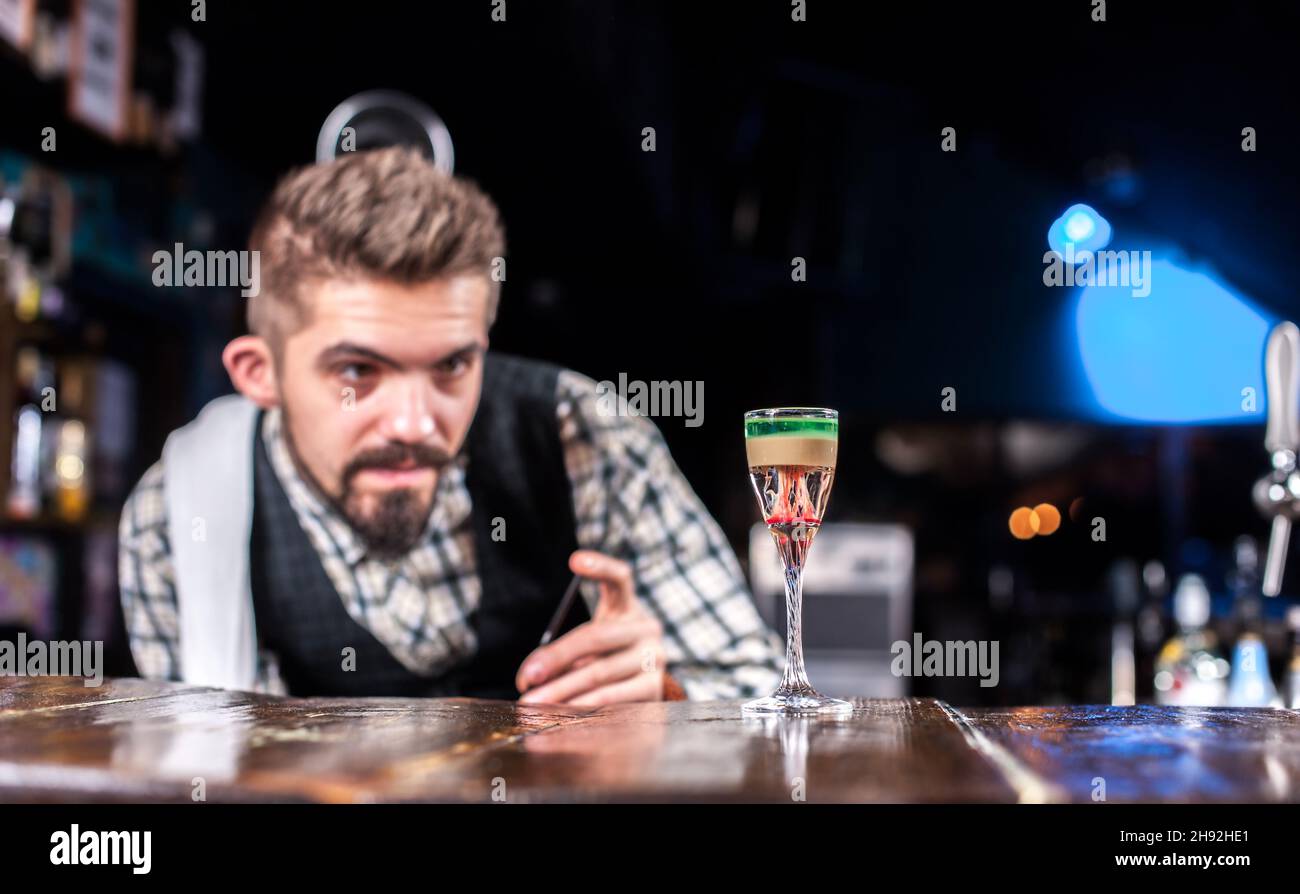 Charming bartender pouring fresh alcoholic drink into the glasses at the bar counter Stock Photo ...